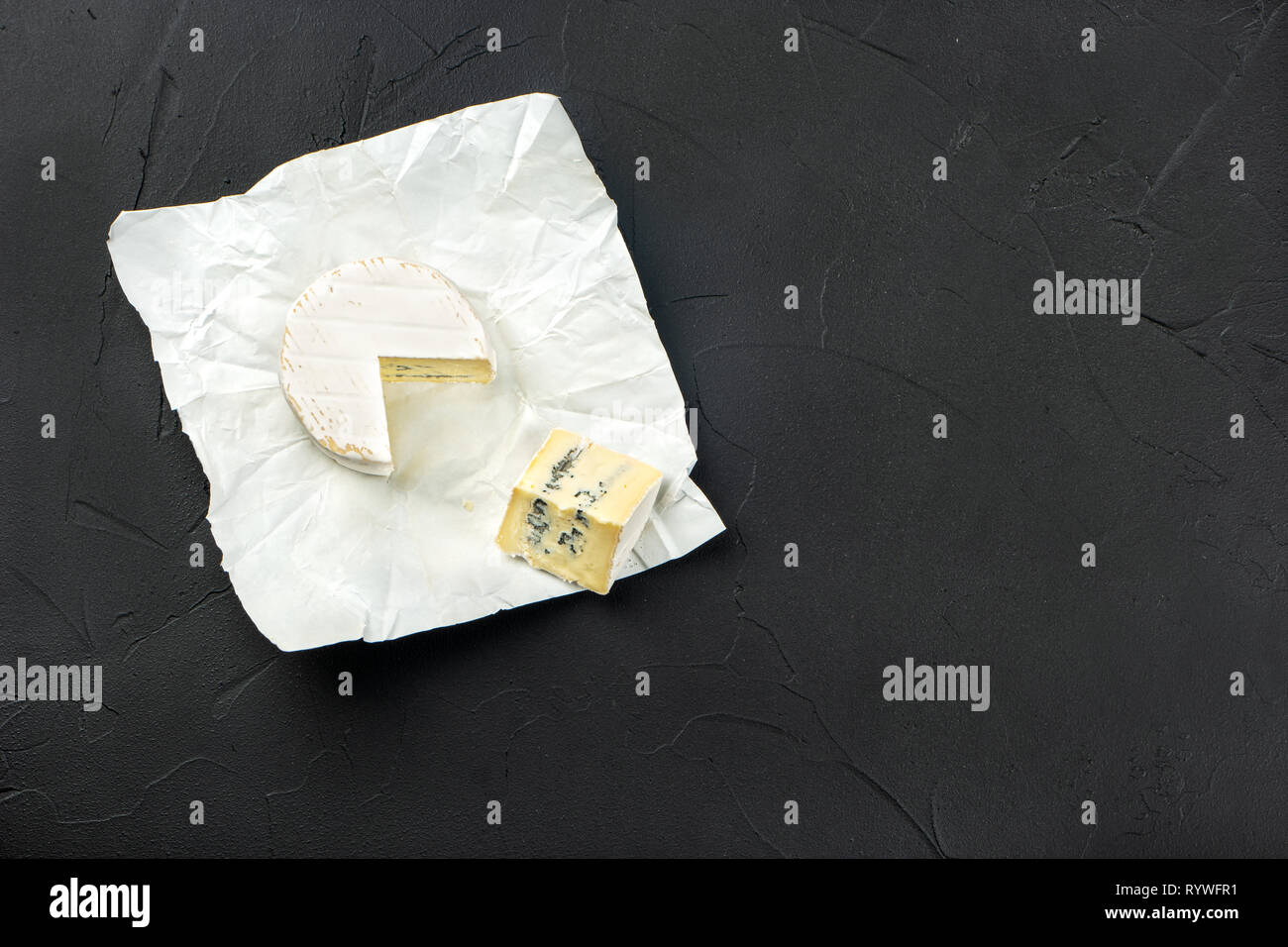 Brie cheese with a slice of paper in the open package on dark ...