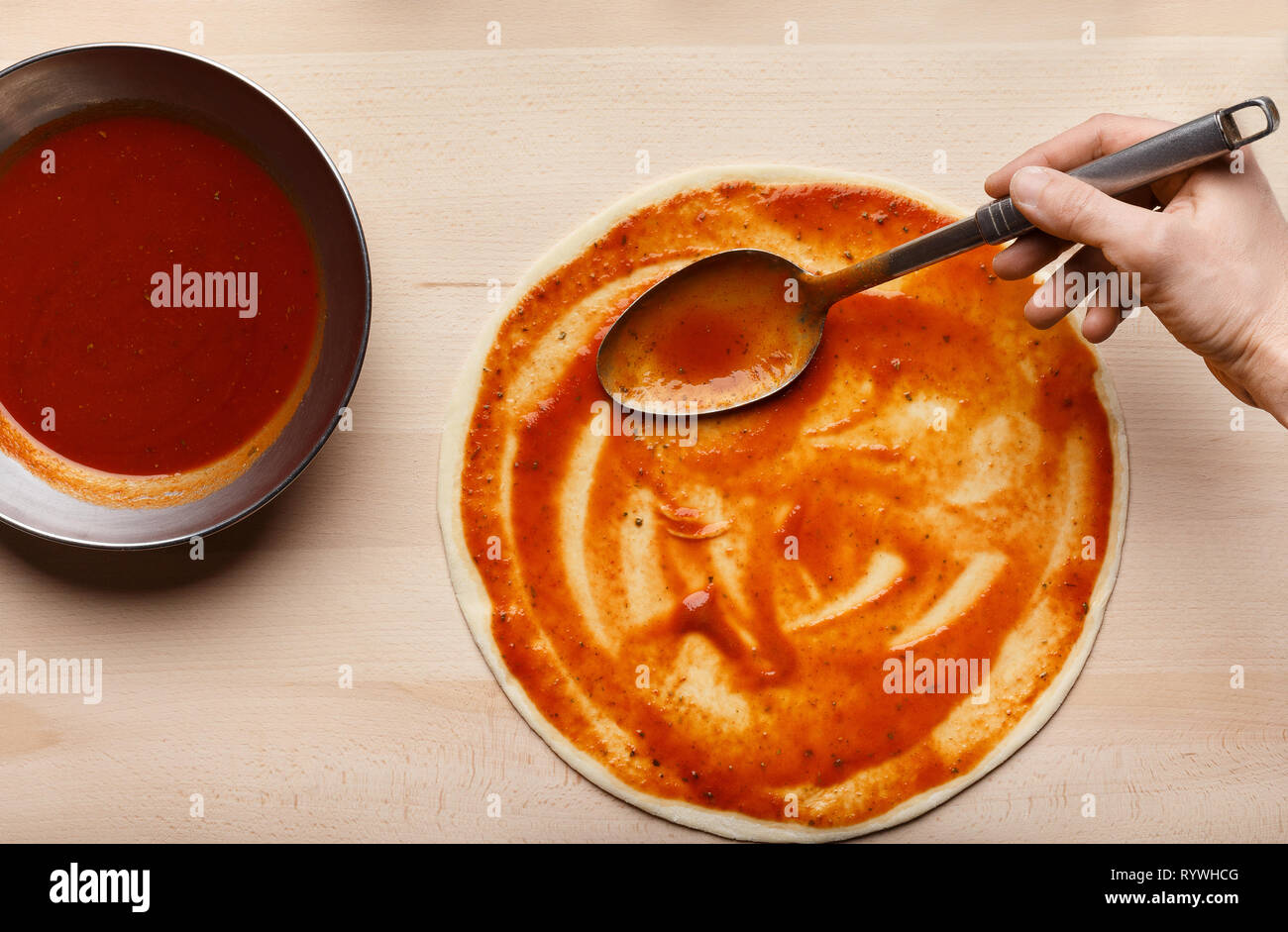 Man spreading tomato paste on pizza base Stock Photo - Alamy