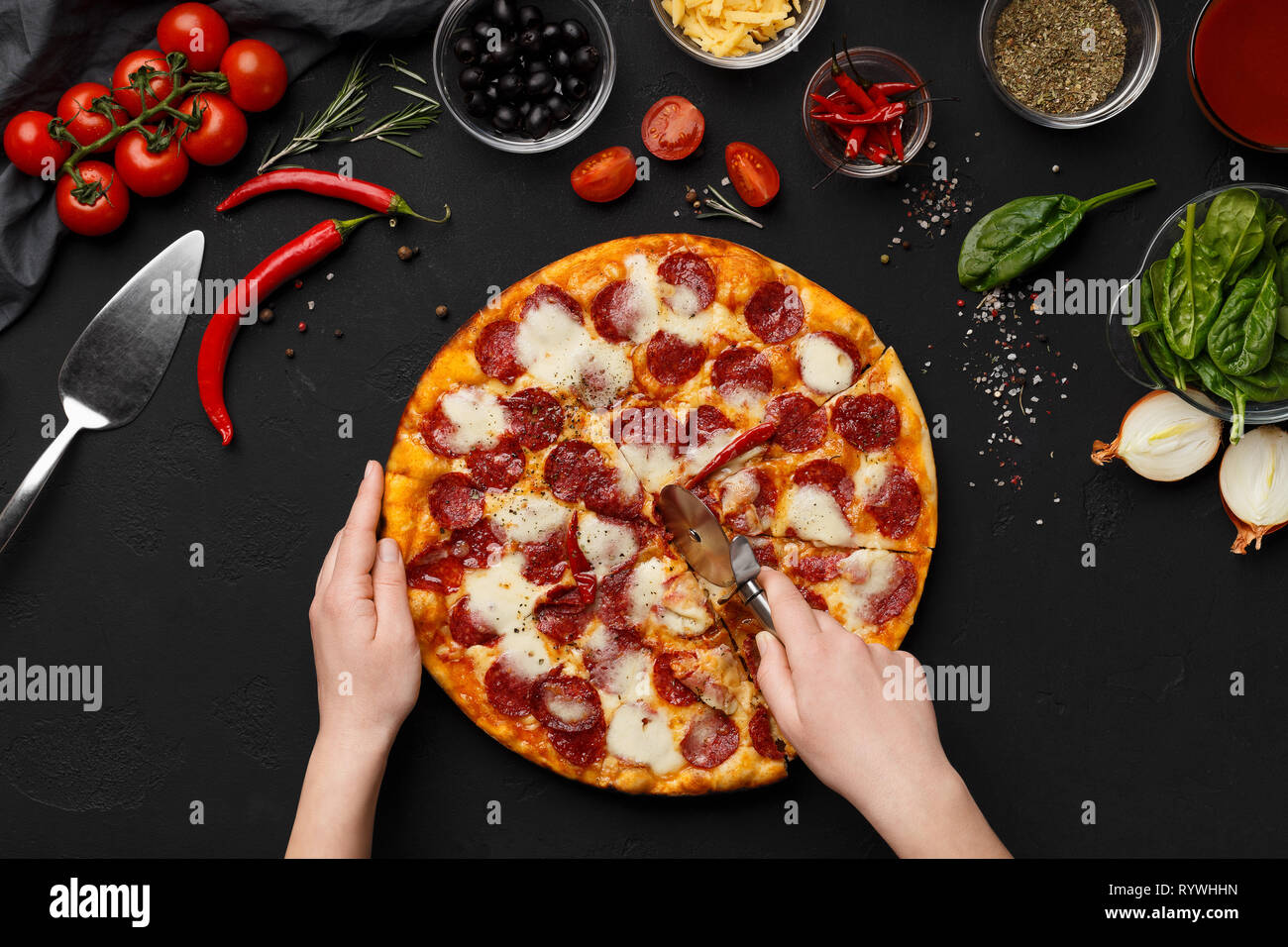 Woman cutting pepperoni pizza into slices, top view Stock Photo - Alamy