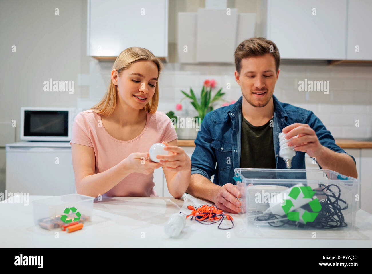 Recycling, reuse, energy. Young family sorting light bulbs, batteries ...