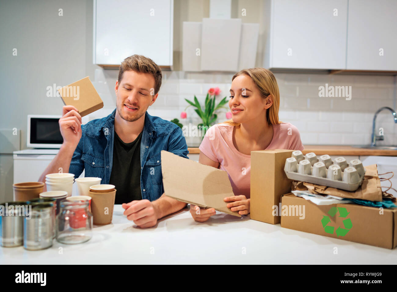 Recycling. Young family sorting paper while sitting at the table filled ...