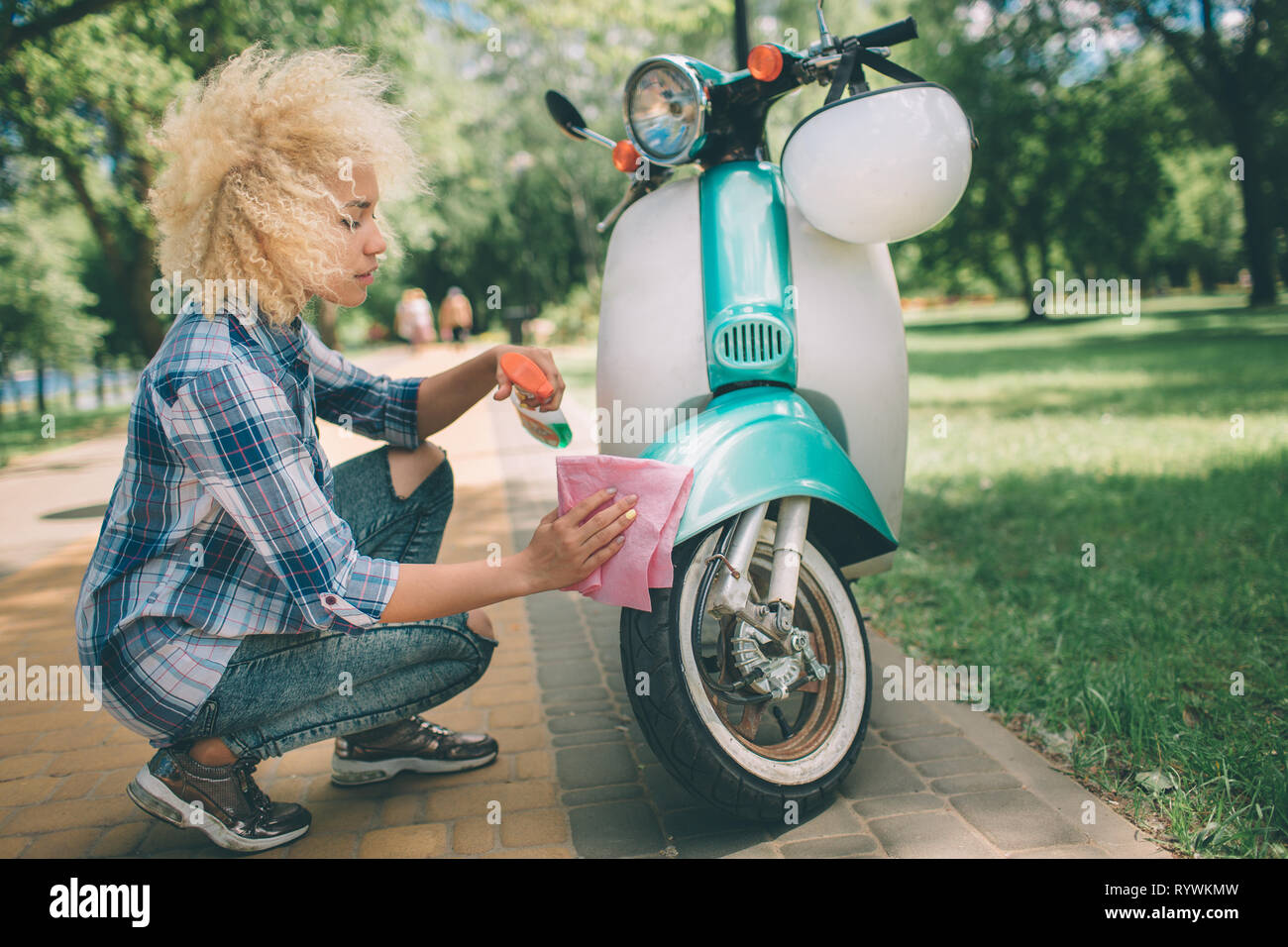 African American women washing motor scooter. Girl cleaning a the blue ...