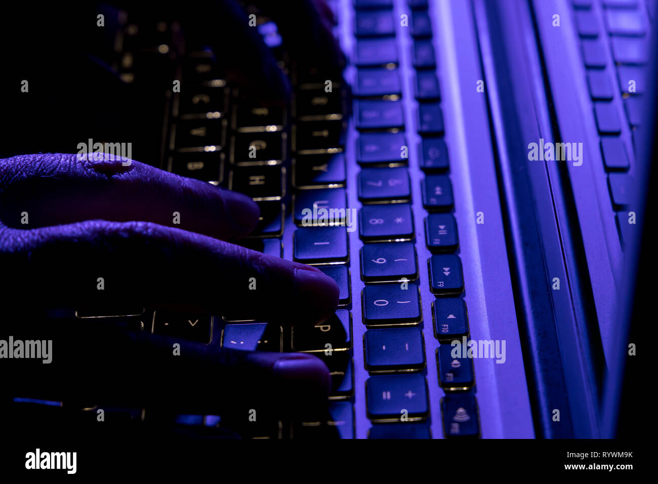Man typing on laptop computer keyboard at night online cyber crime ...