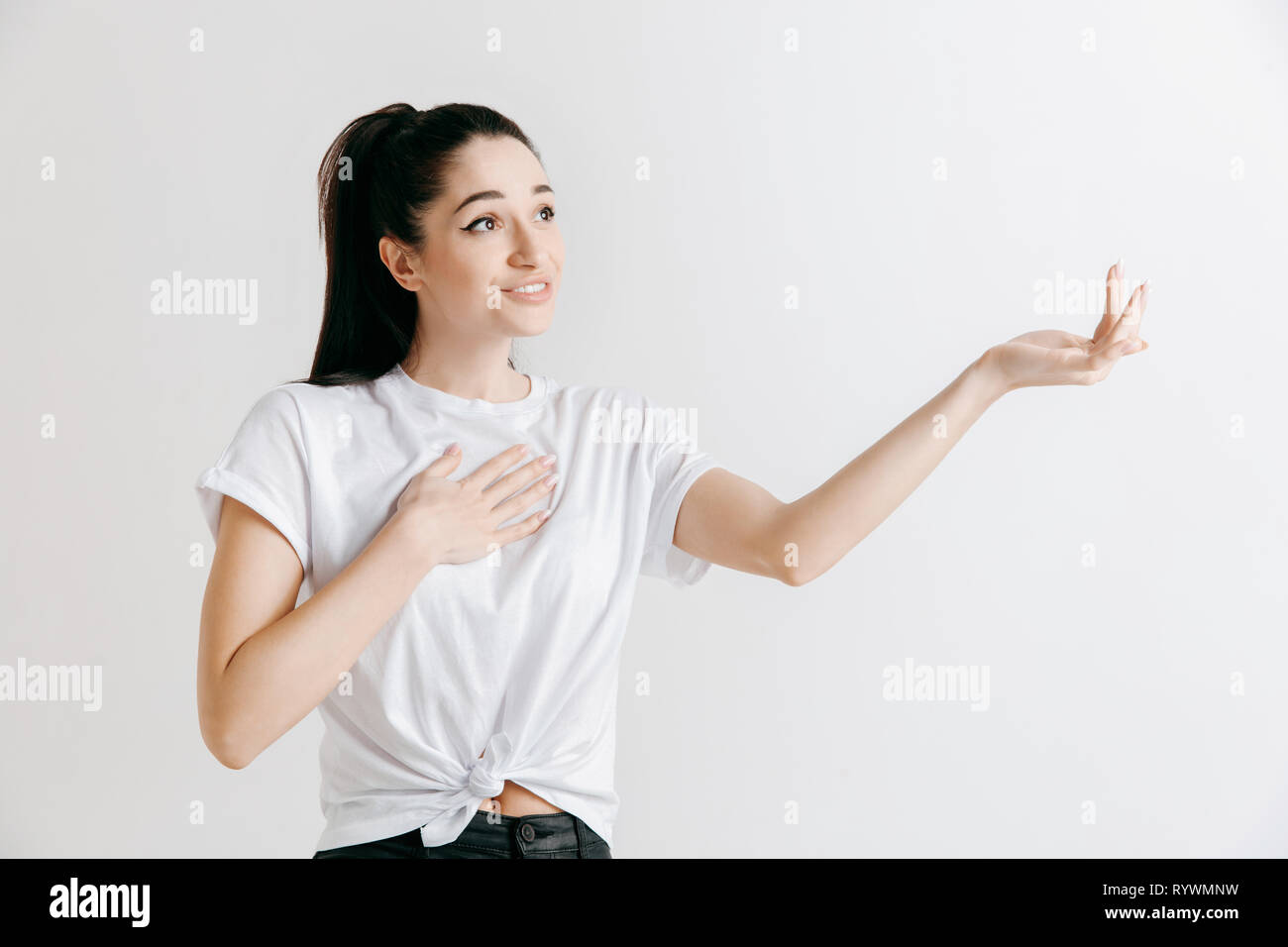 Happy woman standing and presenting something isolated on gray studio ...