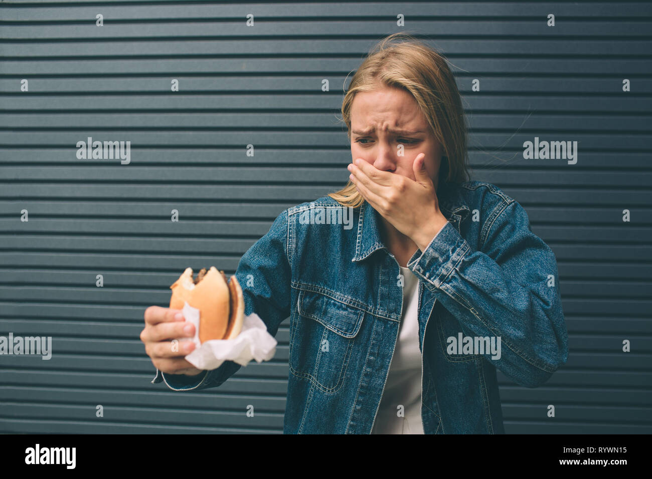 Young woman eating fast food outdoor and feels very bad Stock Photo - Alamy