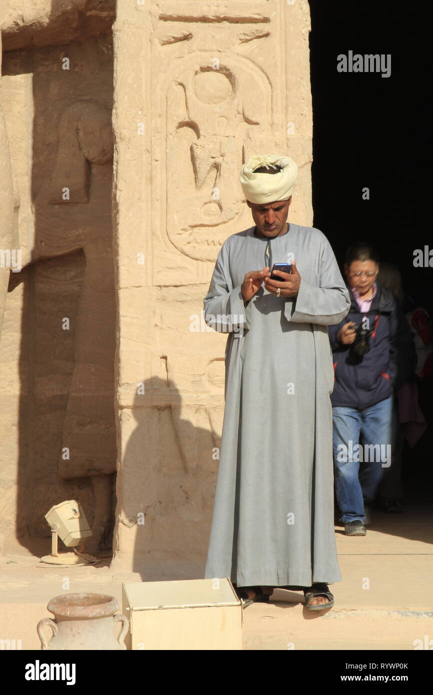 Temple Guard in traditional dress checking his cell phone, Abu Simbel ...
