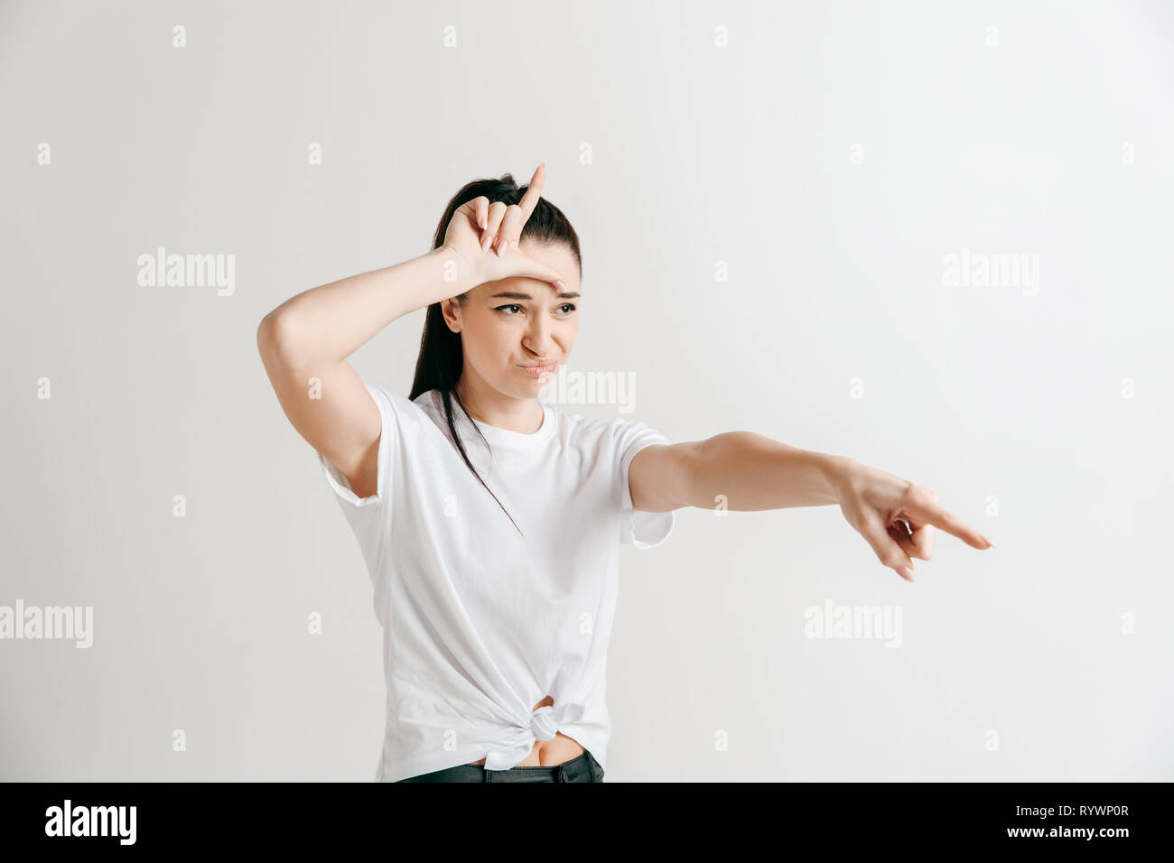 Losers go home. Portrait of smiling woman showing loser sign over ...