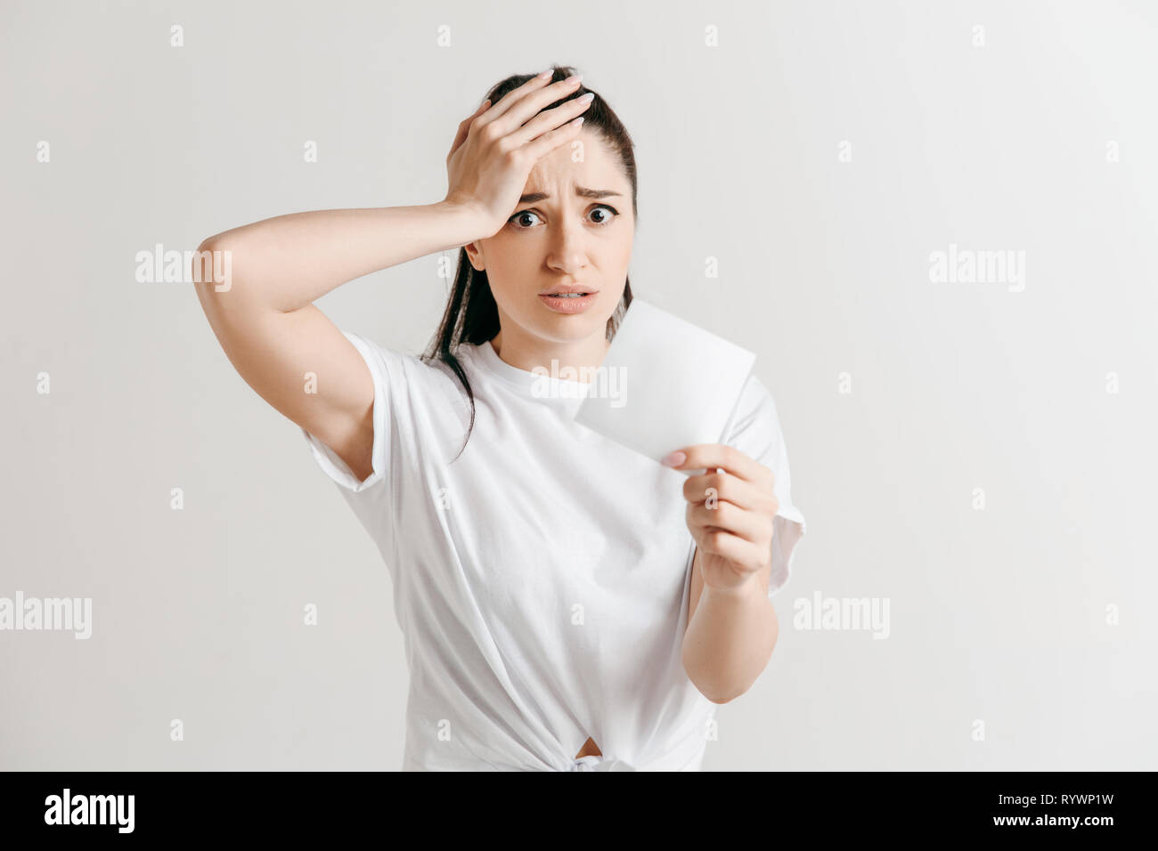 Young woman with a surprised unhappy expression lost a bet on studio ...