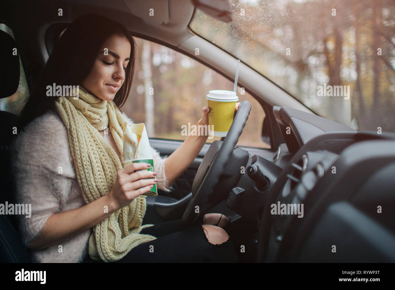 Pretty woman eating food and driving in her car Stock Photo - Alamy