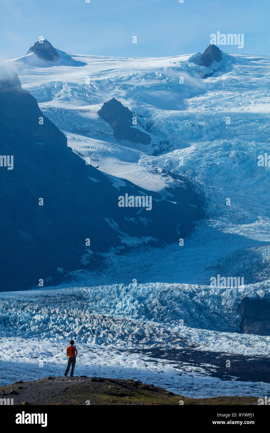 Person dwarfed by the ice fall of Kviarjokull glacier. Vatnajokull ice ...