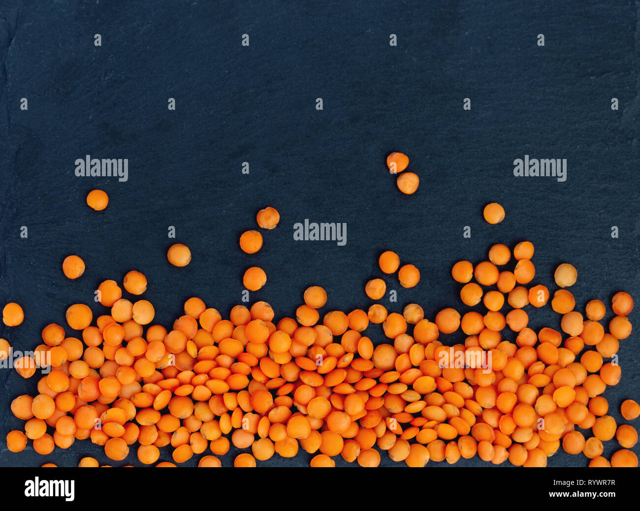 Orange lentil lies on a black stone background Stock Photo - Alamy