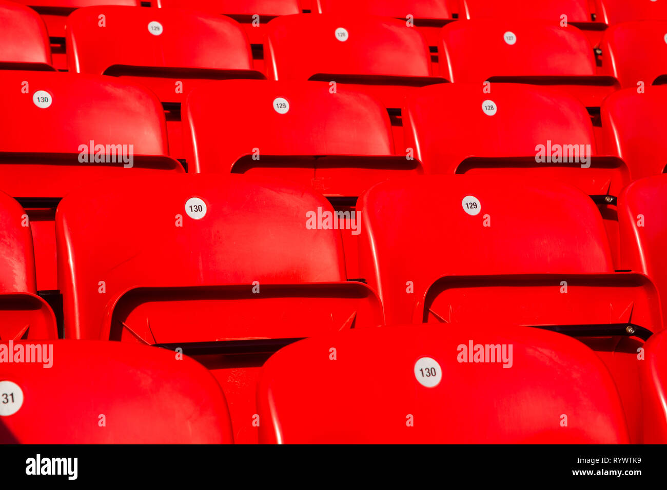 Rows of numbered foldable shiny red plastic seating for fans on ...