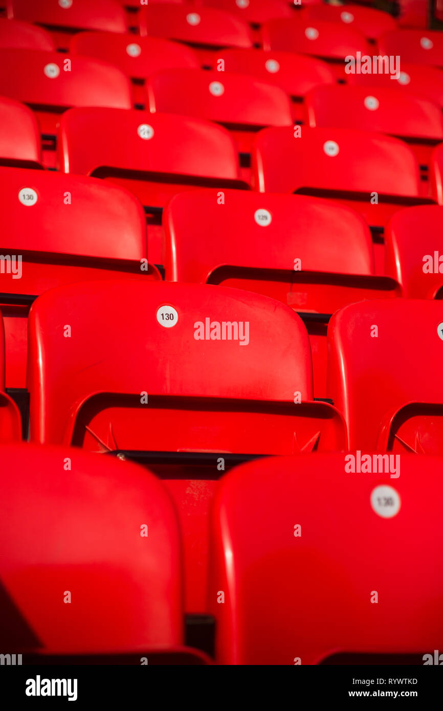 Rows of numbered foldable shiny red plastic seating for fans on ...