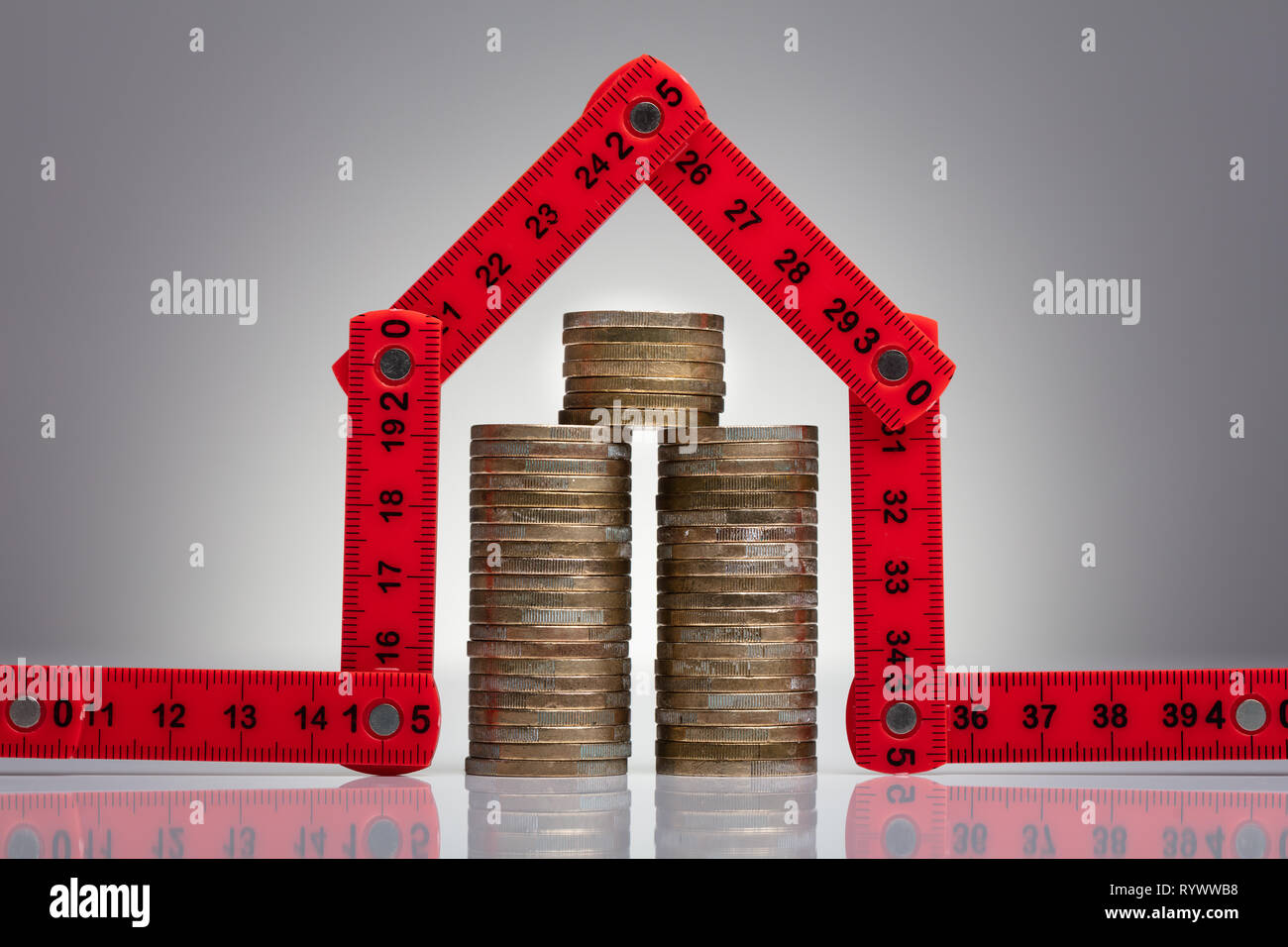 Stack Of Coins Under The House Made With Red Measuring Tape On The Desk ...