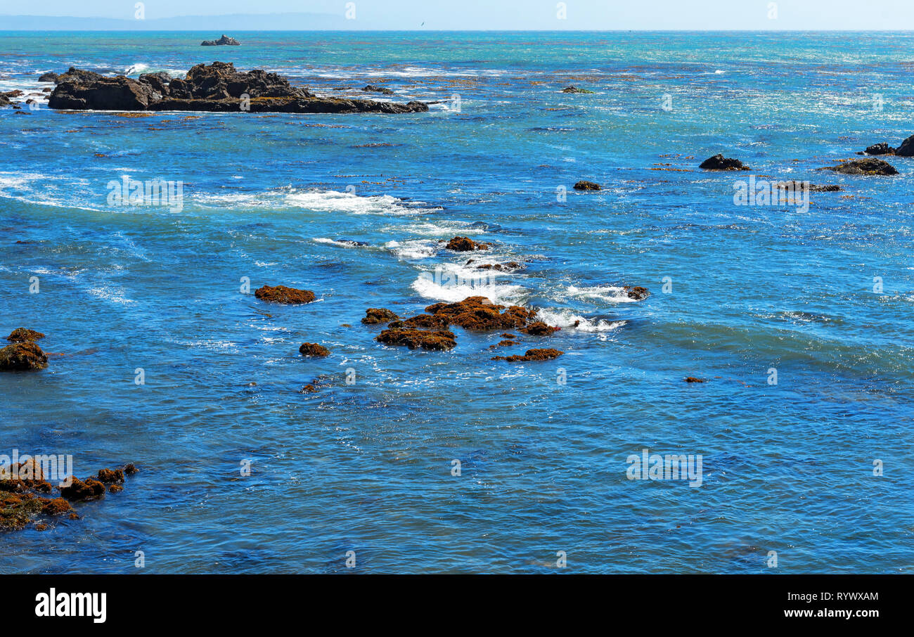 Ocean waves breaking onto rocks in blue sea Stock Photo - Alamy