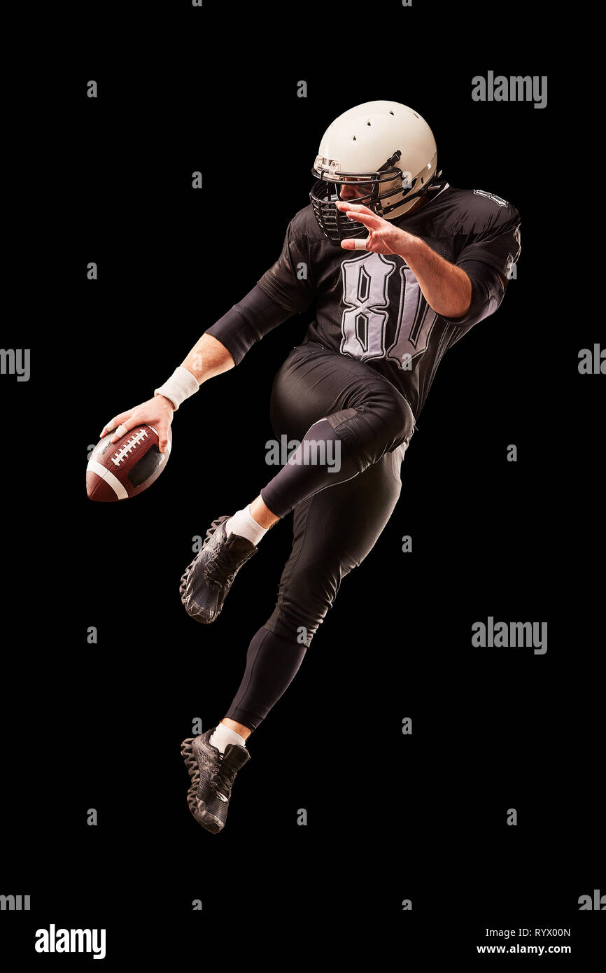 American football player in a jump with a ball on a black background ...