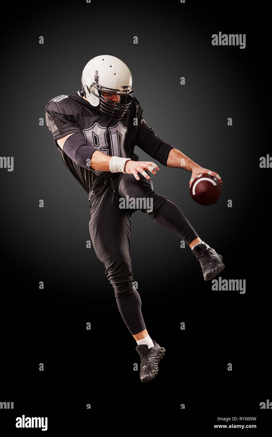 American football player in a jump with a ball on a black background ...