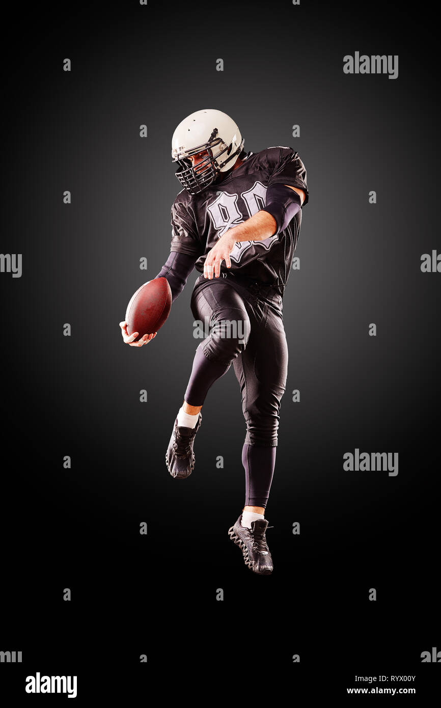 American football player in a jump with a ball on a black background ...
