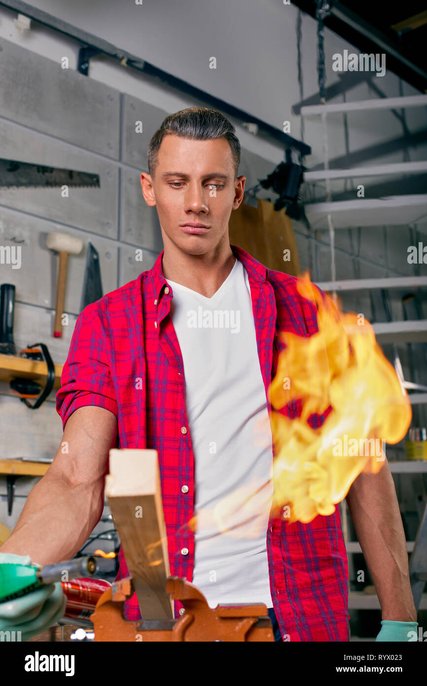 Expert carpenter burning a wood leg with a professional gas burner ...