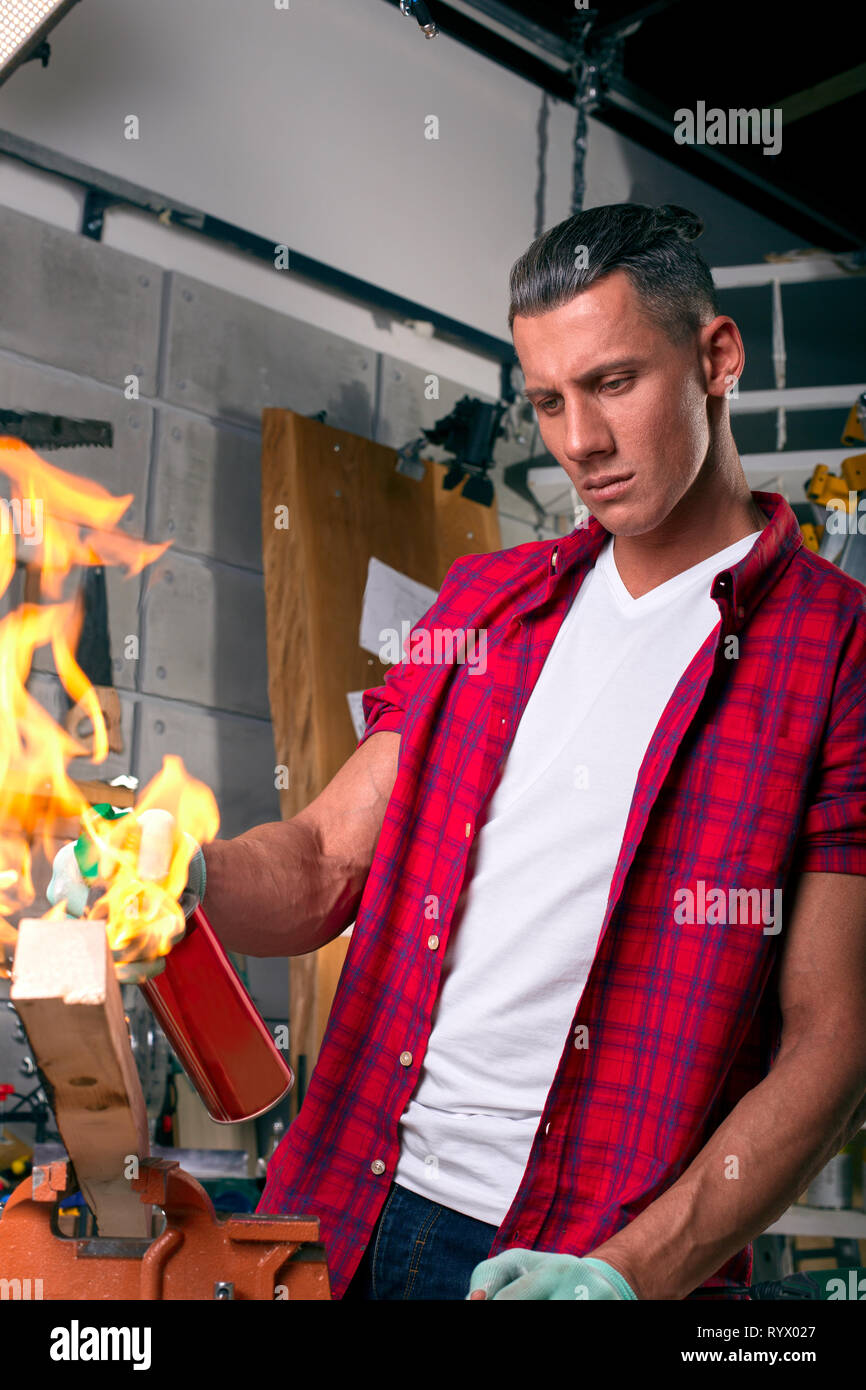 Expert carpenter burning a wood leg with a professional gas burner ...