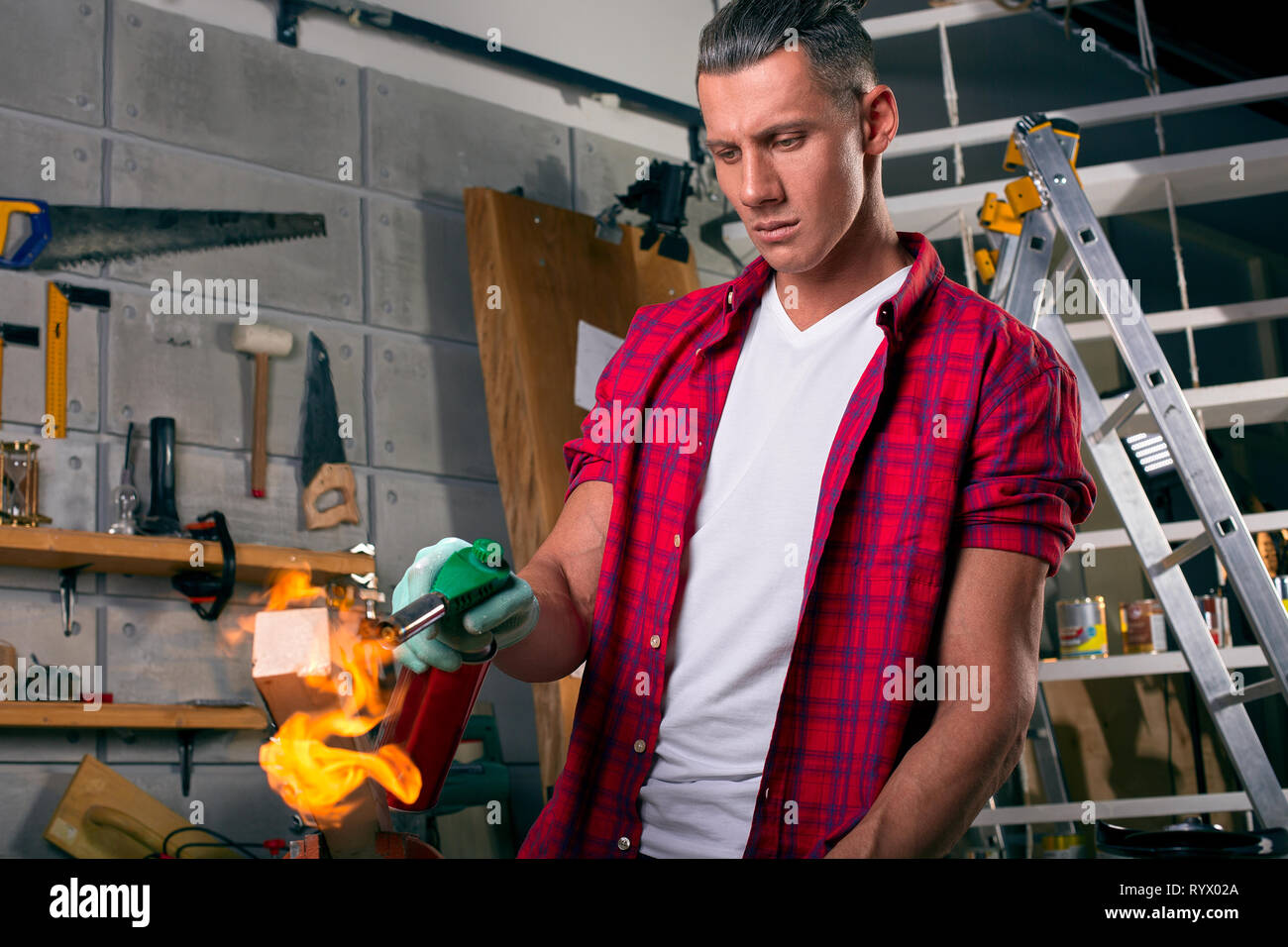 Expert carpenter burning a wood leg with a professional gas burner ...