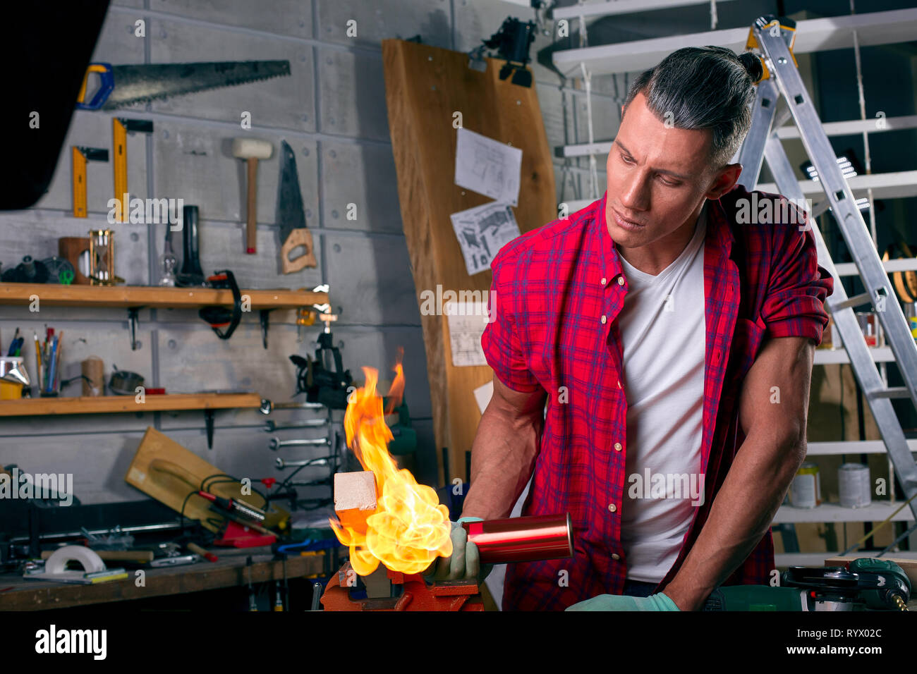 Expert carpenter burning a wood leg with a professional gas burner ...
