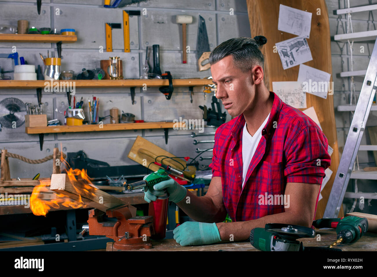 Expert carpenter burning a wood leg with a professional gas burner ...