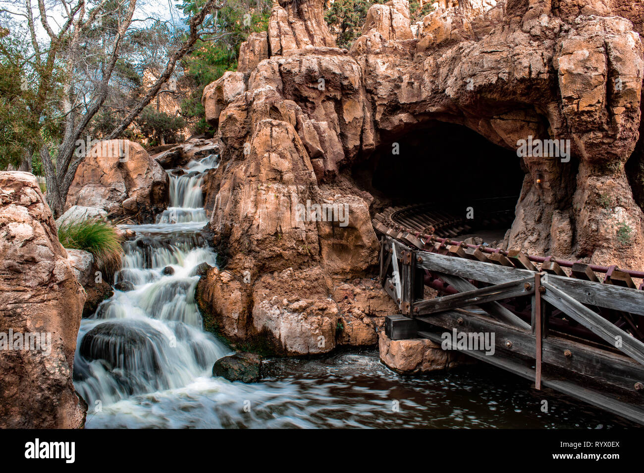 A mining car track twisting into a mountain framed with red rock and ...