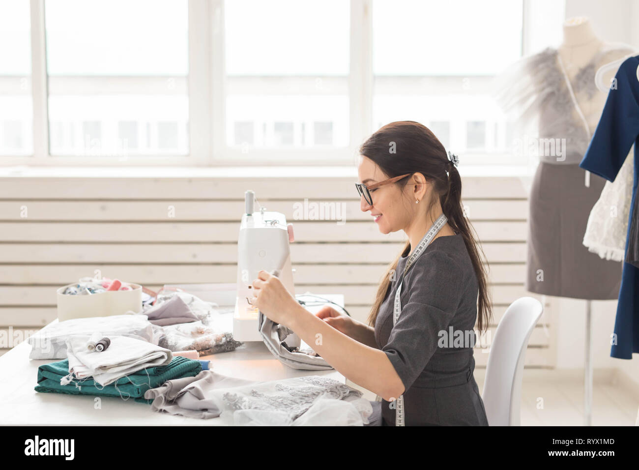 People and fashion concept - Young dressmaker woman sews clothes on ...