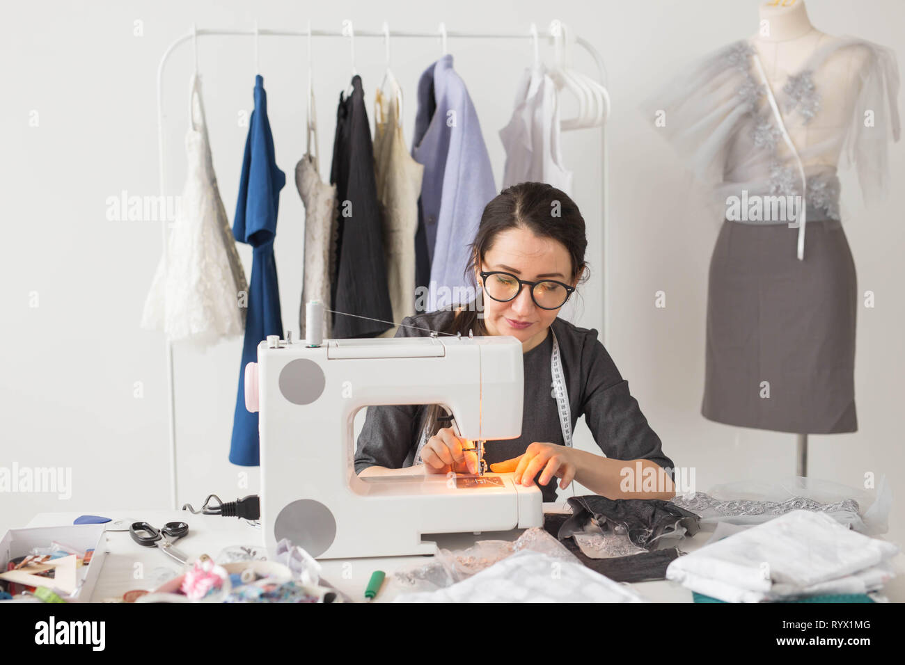 People and fashion concept - Young dressmaker woman sews clothes on ...