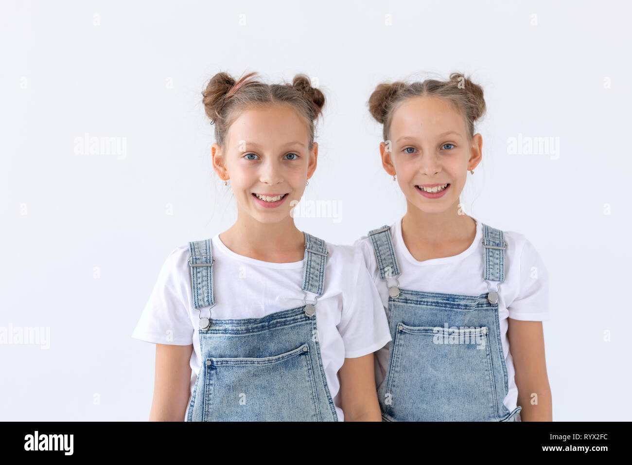 Family and love concept - two smiling twin sisters hugging over white ...