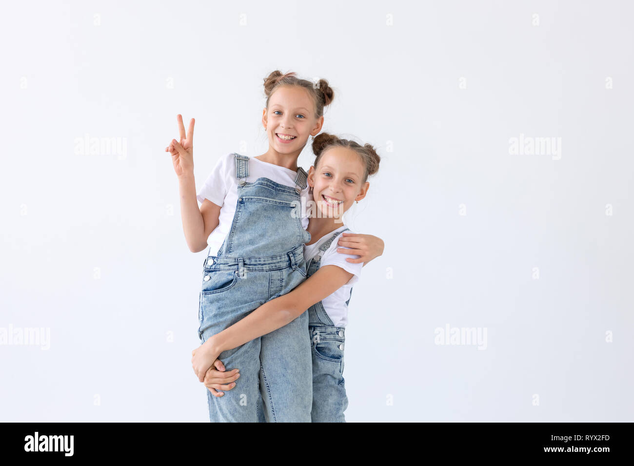 Family and love concept - two smiling twin sisters hugging over white ...
