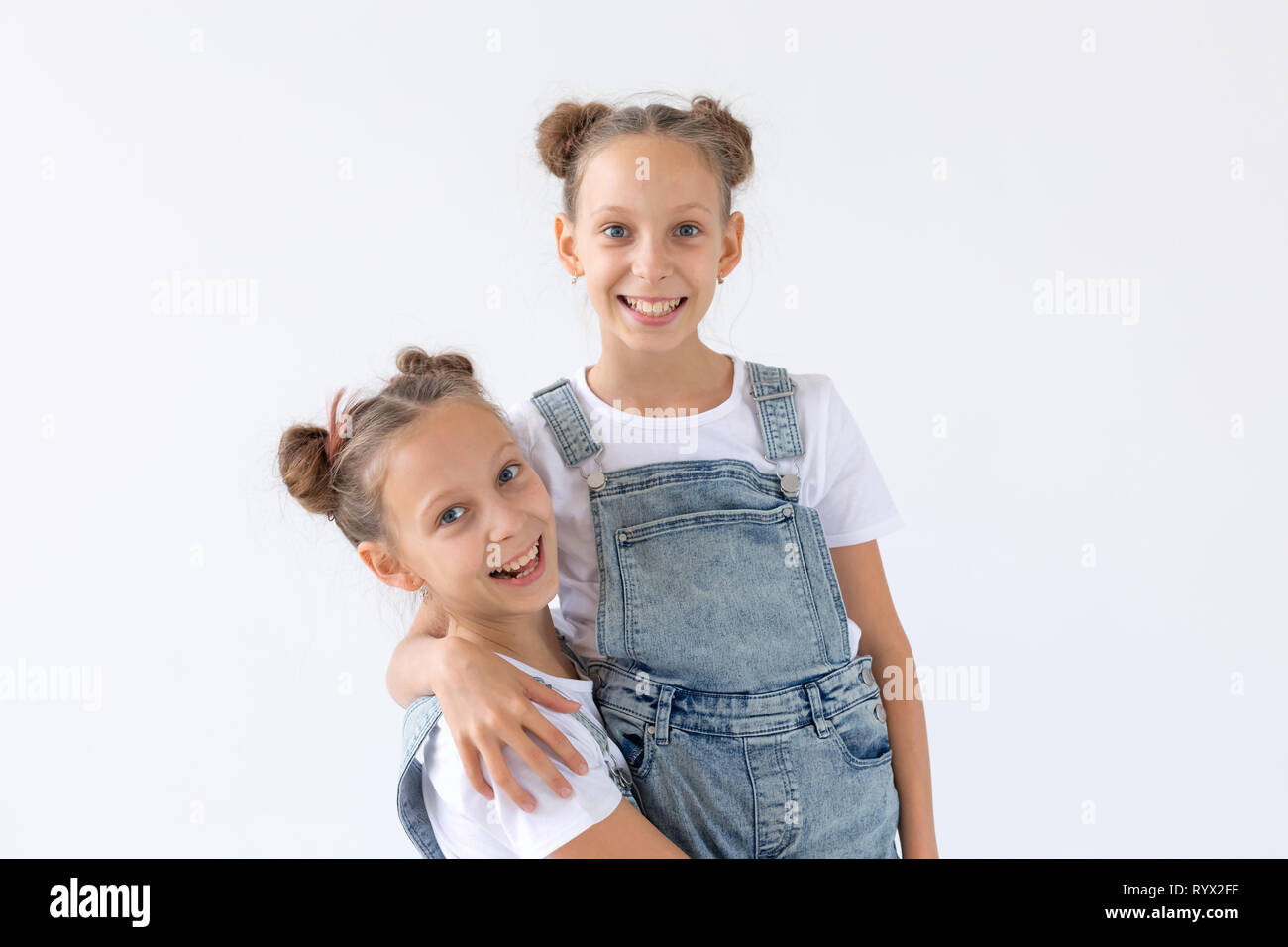 Family and love concept - two smiling twin sisters hugging over white ...