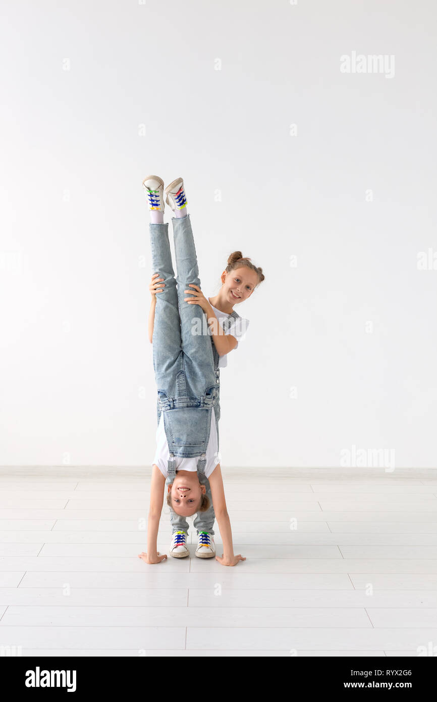 Family and sport concept - Two acrobat twin girls are standing on the ...