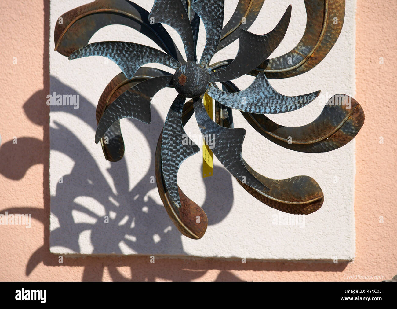 Large garden wind spinner on display outside casting shadow on wall ...