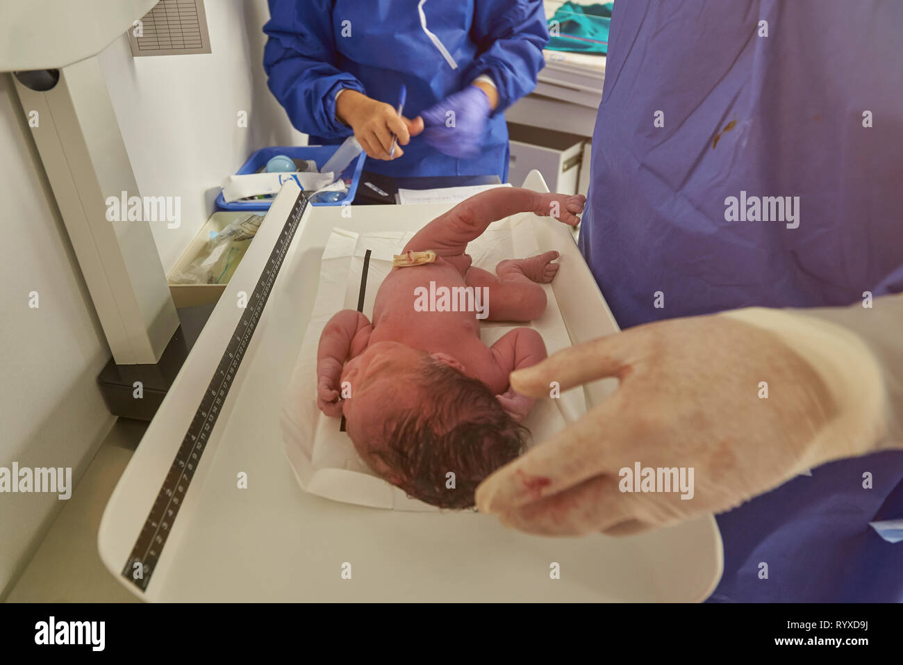Measuring weight of newborn baby in hospital background Stock Photo - Alamy