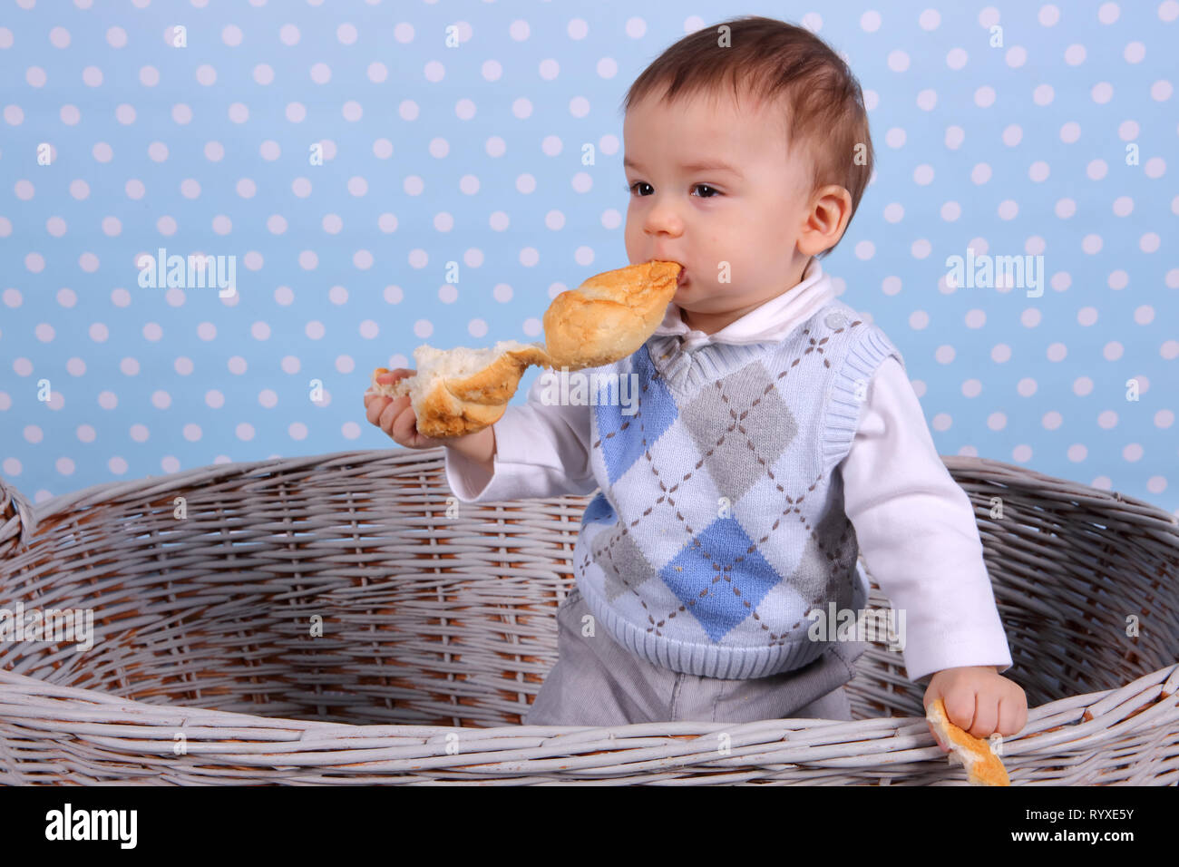 A tiny child eats a dry bun in a basket woven from a wicker tree Stock ...
