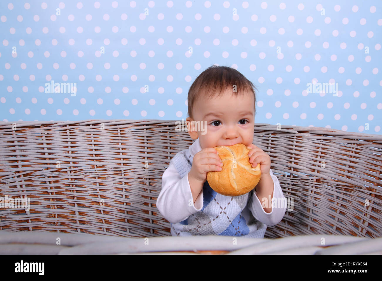 A tiny child eats a dry bun in a basket woven from a wicker tree Stock ...