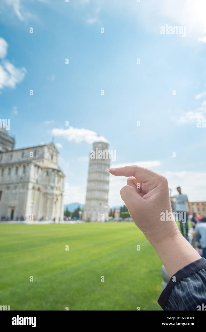 Hand pointing at Leaning Tower of Pisa, one of the most famous landmark ...
