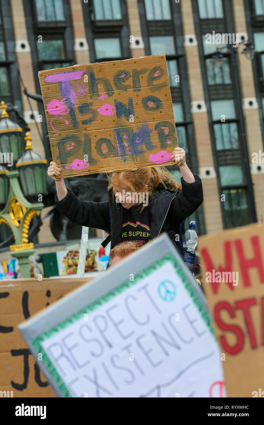 A girl is seen holding a placard on top of another demonstrator during ...