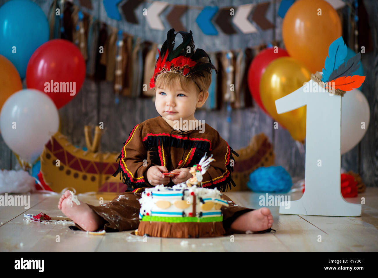 little cute boy in costume of American Indian Apache Chief sits and ...