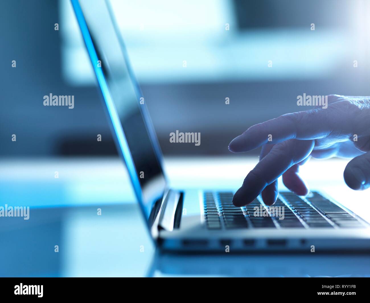 Man typing on a laptop computer at his desk Stock Photo - Alamy