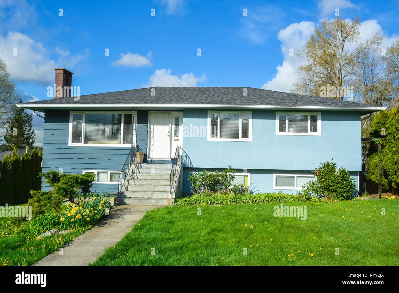 Residential house with landscaped front yard on blue sky background ...