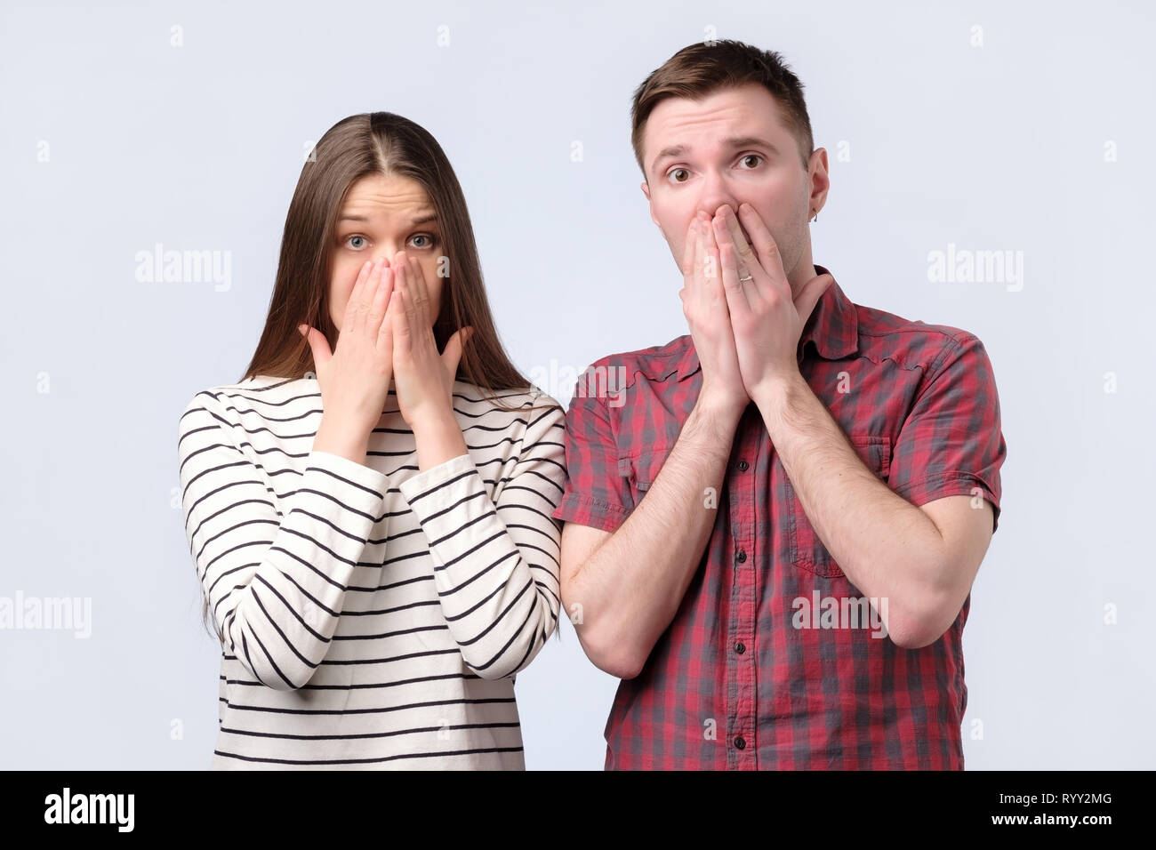 Shocked Amazed Young Couple Covering Mouth With Hands Looking At Camera