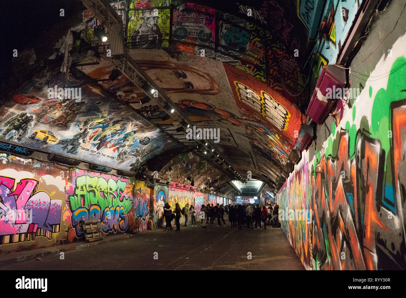 Graffiti painted tunnel with a gathering of people Stock Photo - Alamy