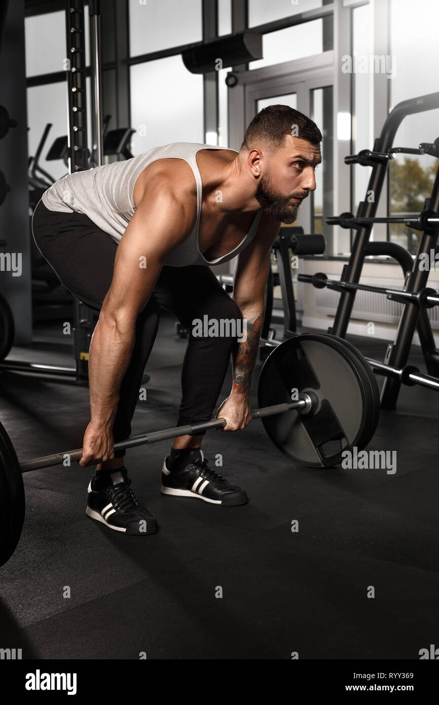 Bodybuilding. Bearded man exercising at gym bending down holding ...