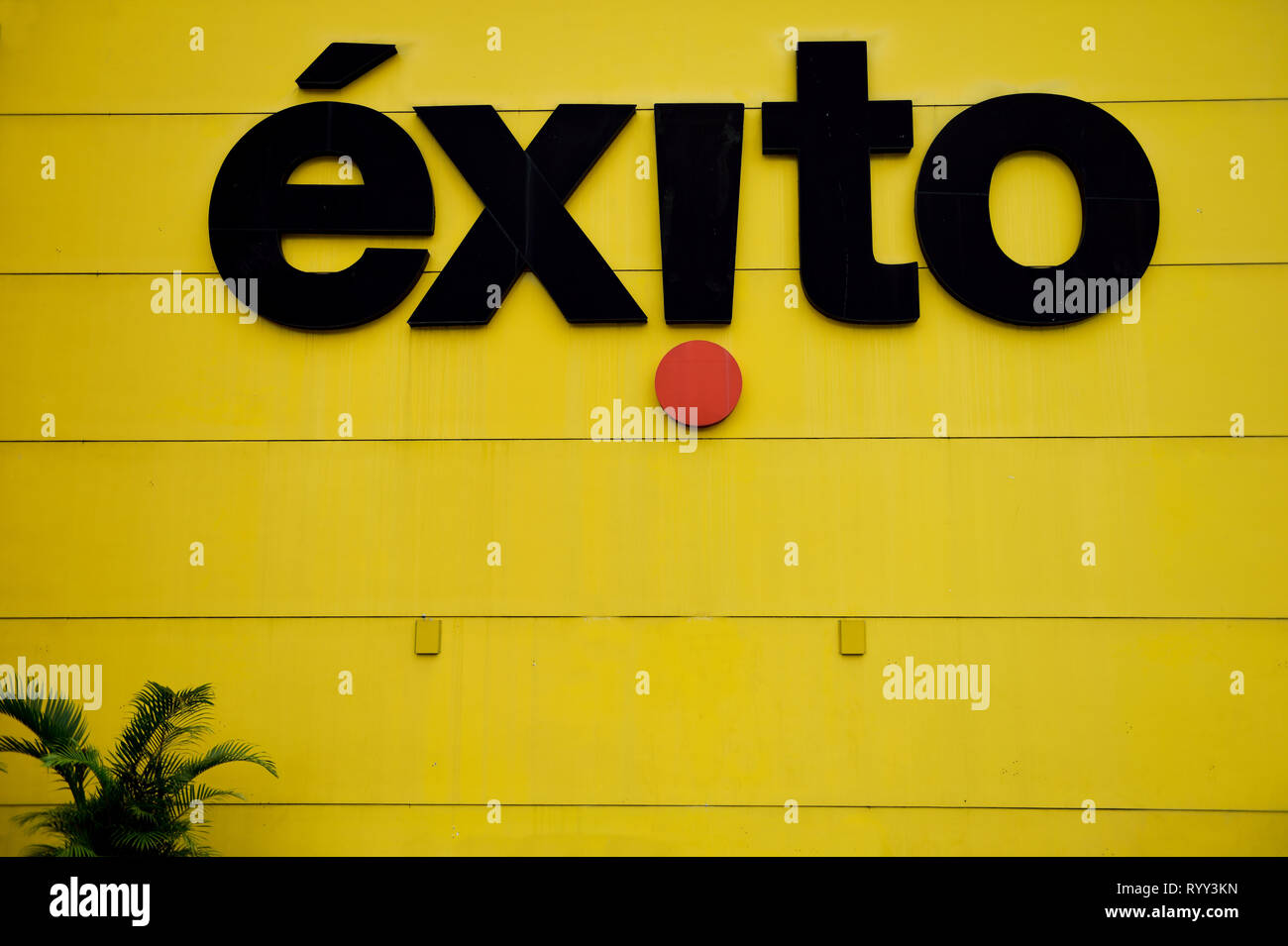An Exito supermarket and department store logo against a yellow ...