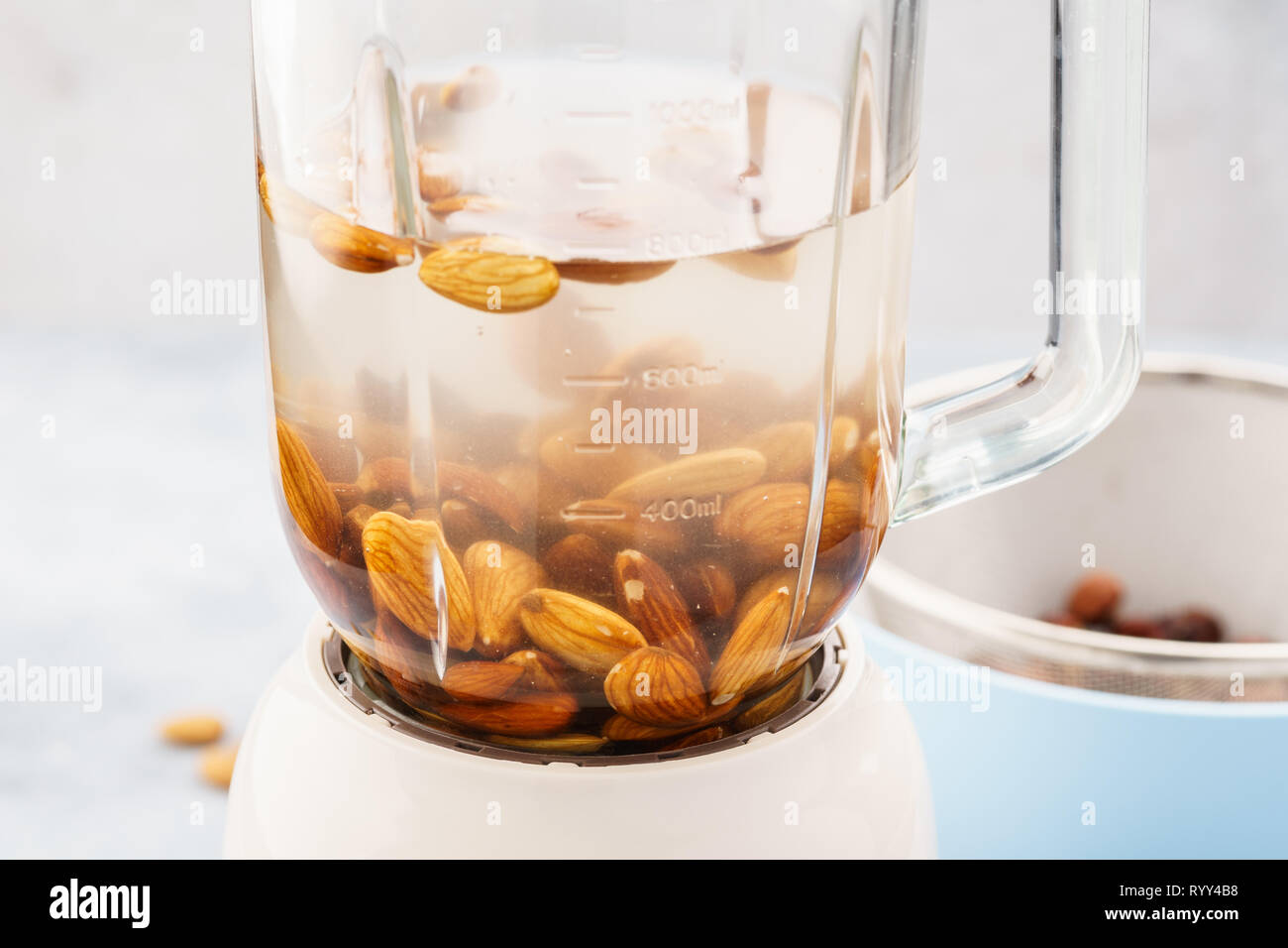 Blender and almonds soaked in water. Making healthy vegan milk Stock ...
