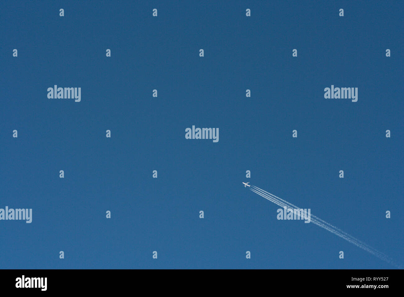 Plane and jetstream flying across the blue sky Stock Photo - Alamy