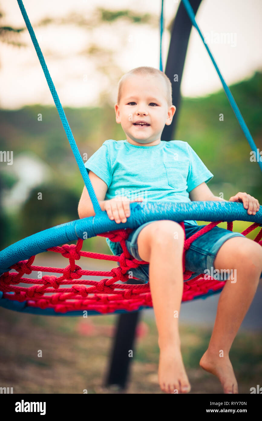 Little boy swinging on a swing at kids playground outdoor Stock Photo ...